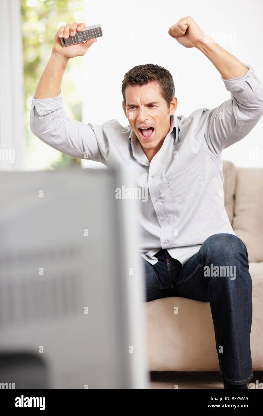 Man cheering in front of television Stock Photo - Alamy