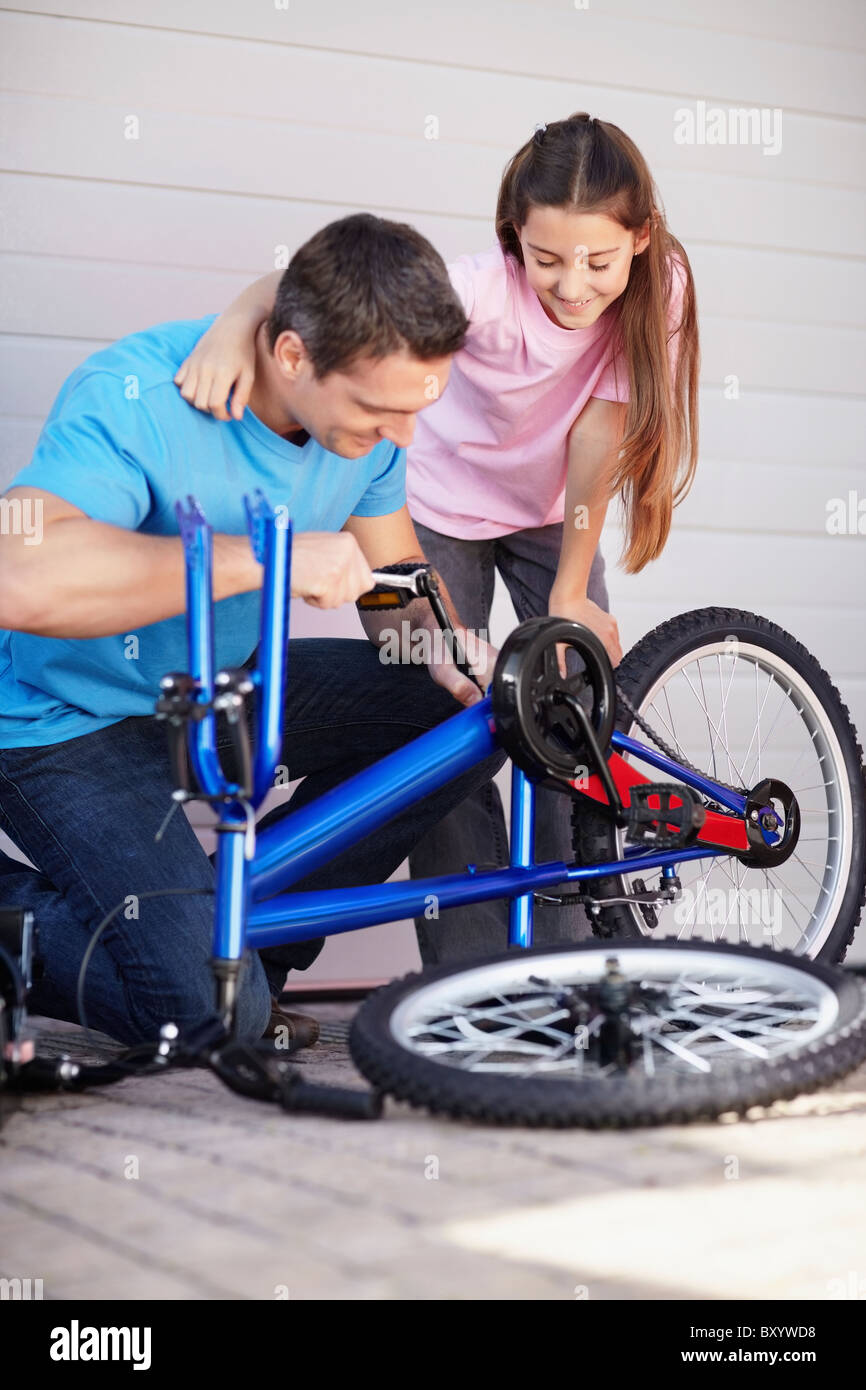 Father with daughter fixing bike Stock Photo - Alamy