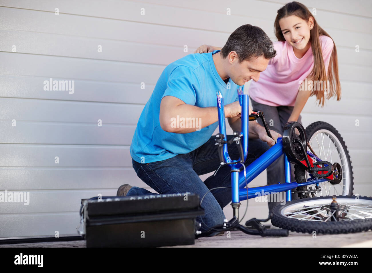 Father with daughter fixing bike Stock Photo - Alamy