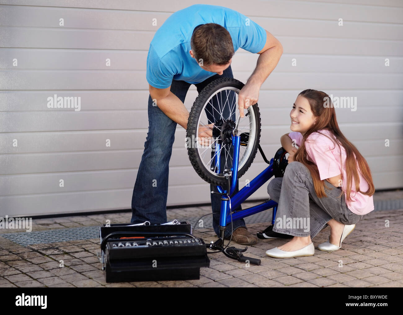 Father with daughter fixing bike Stock Photo - Alamy