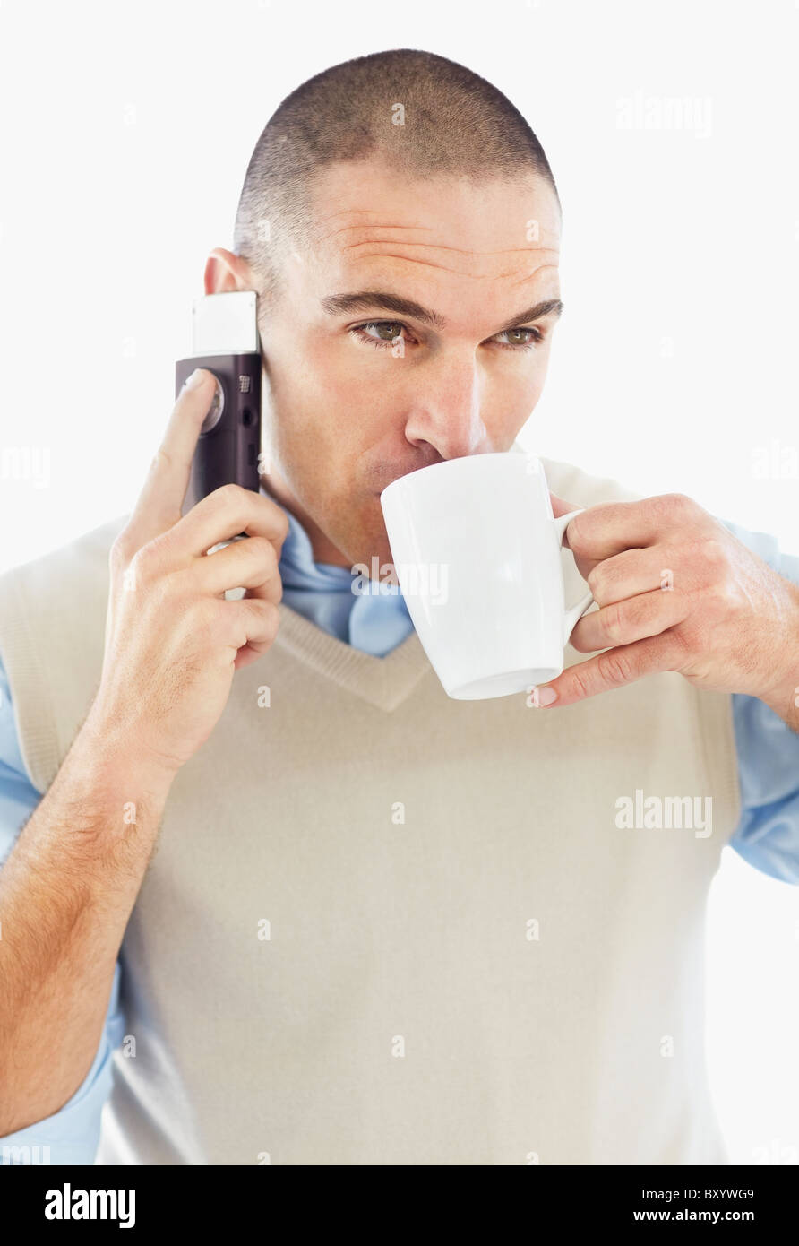 Office worker drinking while using mobile phone Stock Photo - Alamy