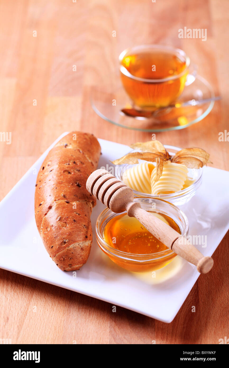 Breakfast of brown roll, butter and honey Stock Photo - Alamy