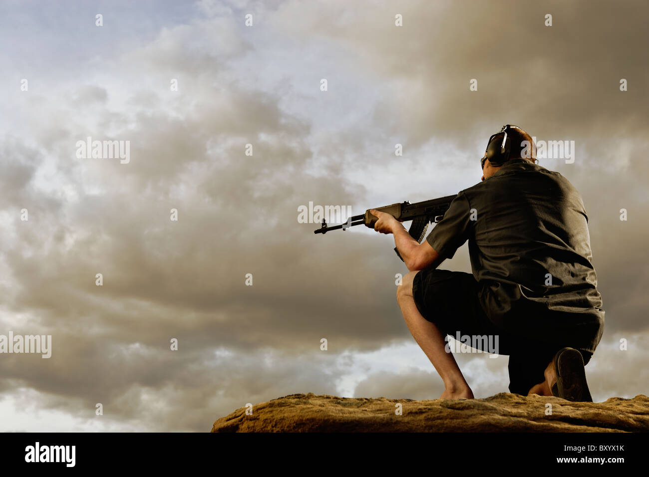 Man aiming gun on rocks Stock Photo - Alamy