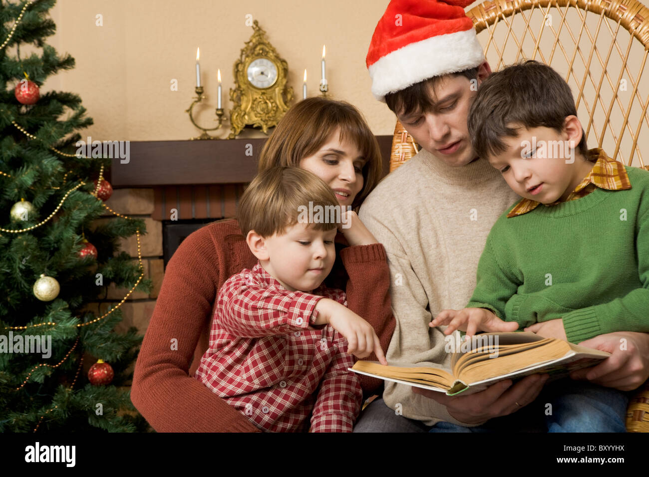 Little brothers pointing at page of book while their father reading it ...