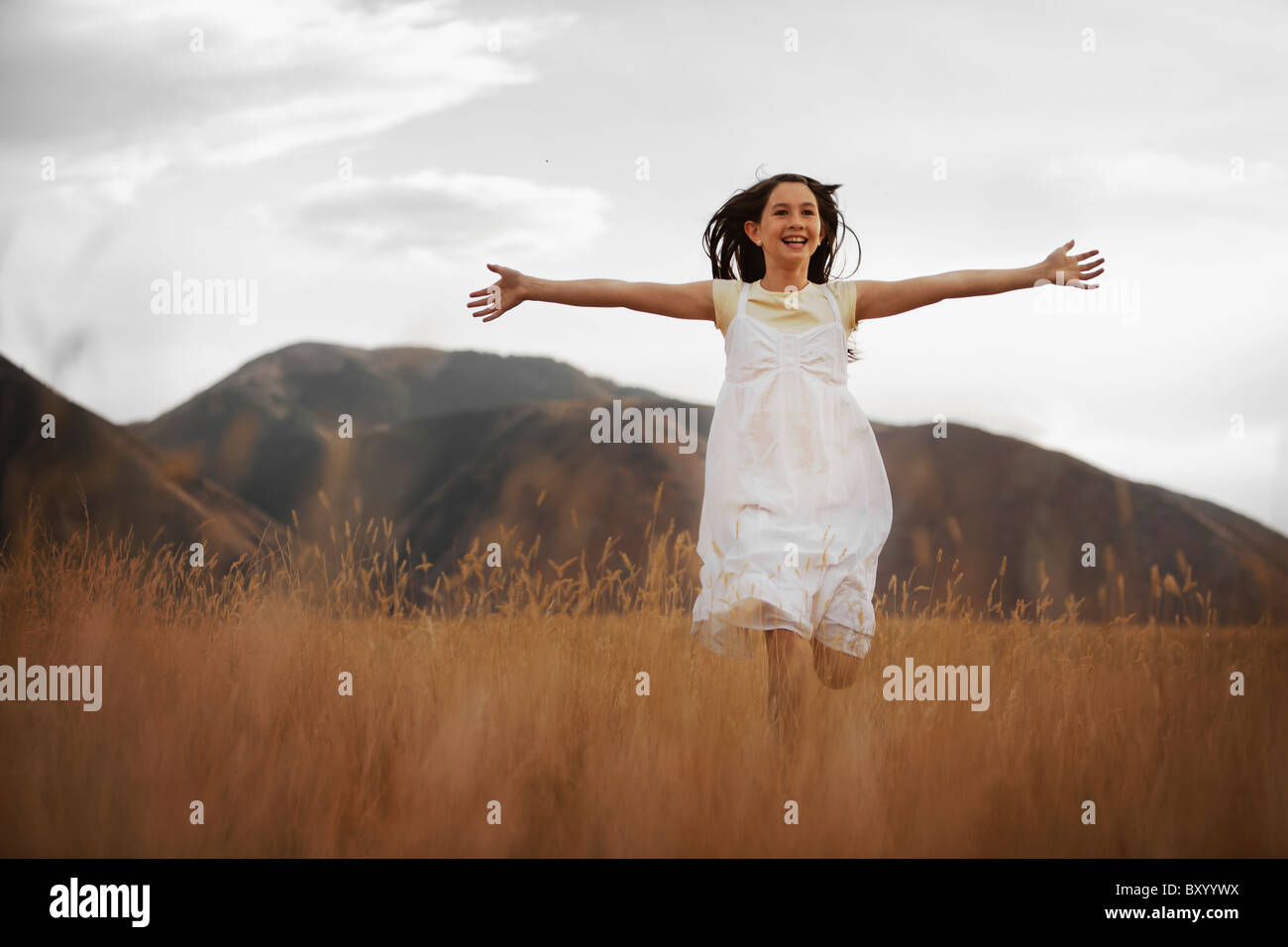 Girl running through wheat field Stock Photo - Alamy