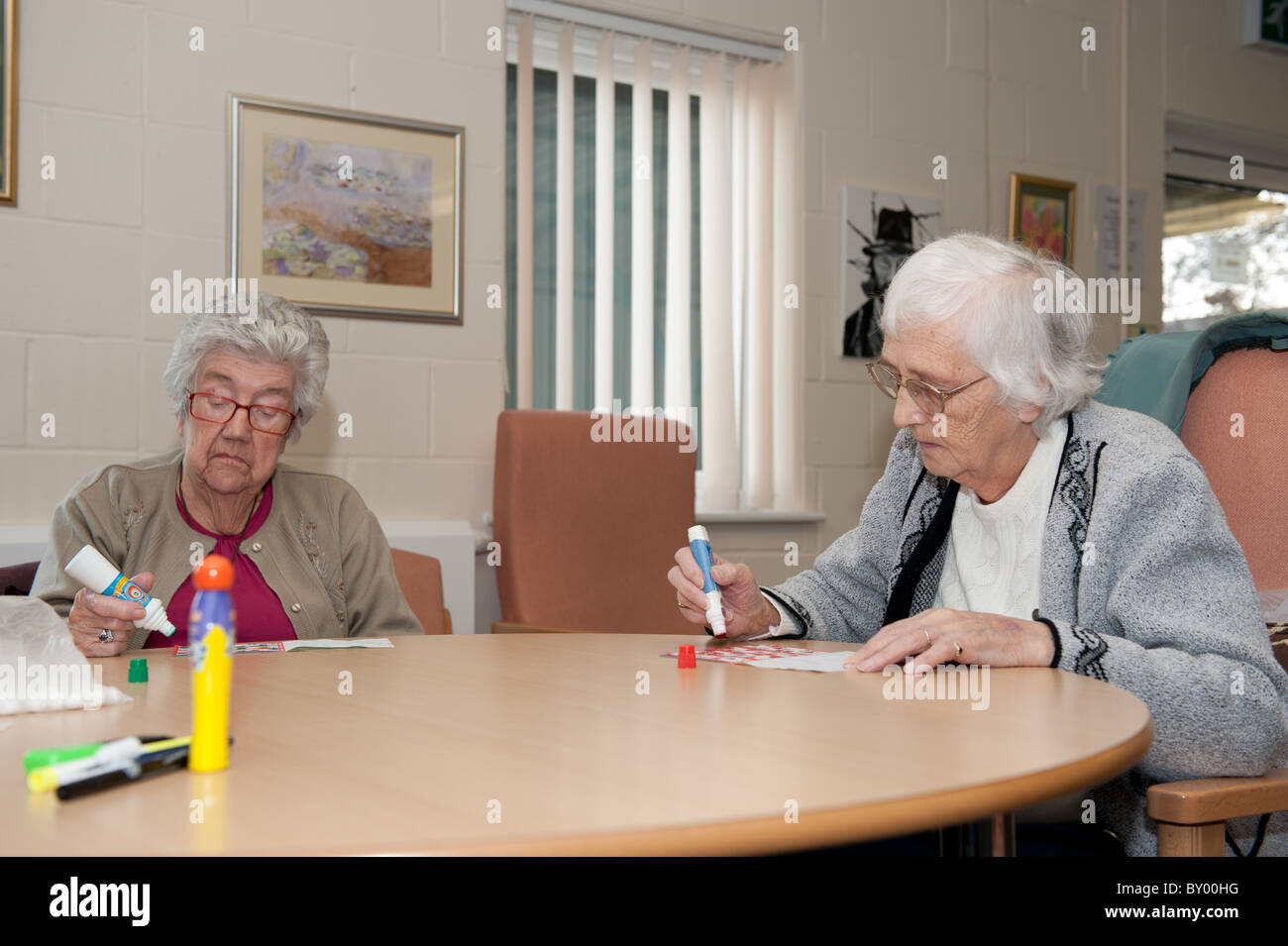 Two elderly ladies sitting at a table playing bingo in UK council run ...