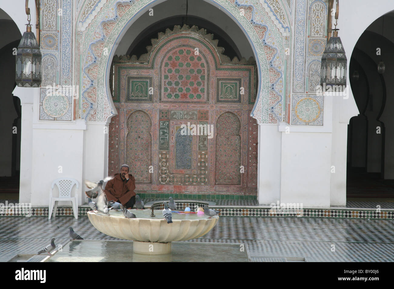 a muslim man in fez morocco sitting in a walled off area of a mosque ...