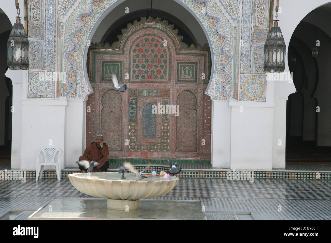 a muslim man in fez morocco sitting in a walled off area of a mosque ...