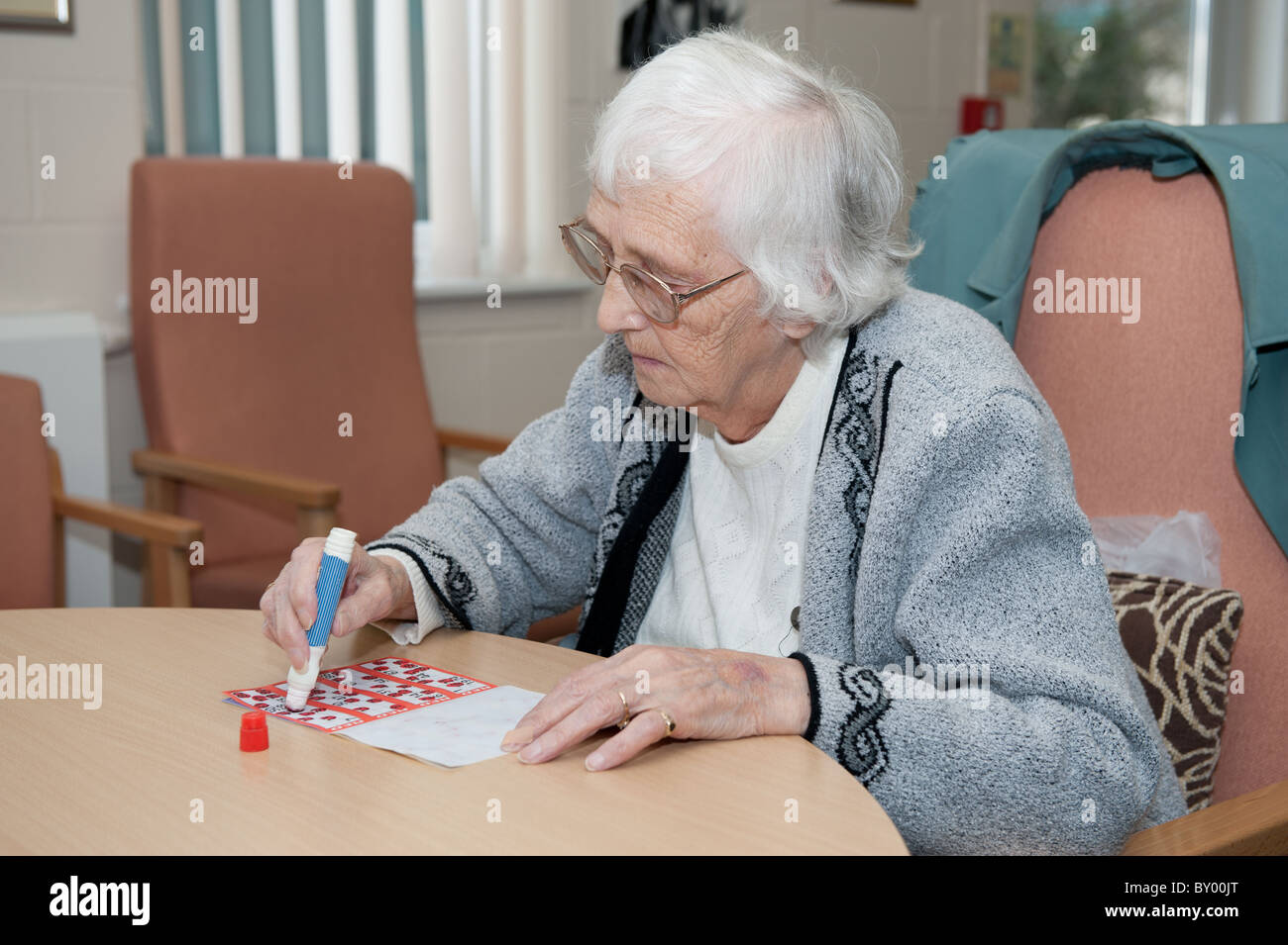 Elderly lady sitting at table playing bingo at council run day centre ...
