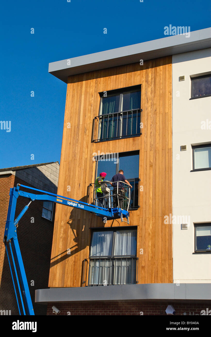 Two people inspecting new window frame on low rise appartments England ...