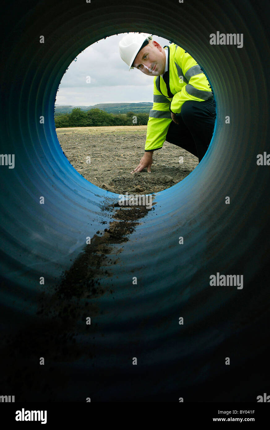 Construction manager looking through a large pipe Stock Photo - Alamy