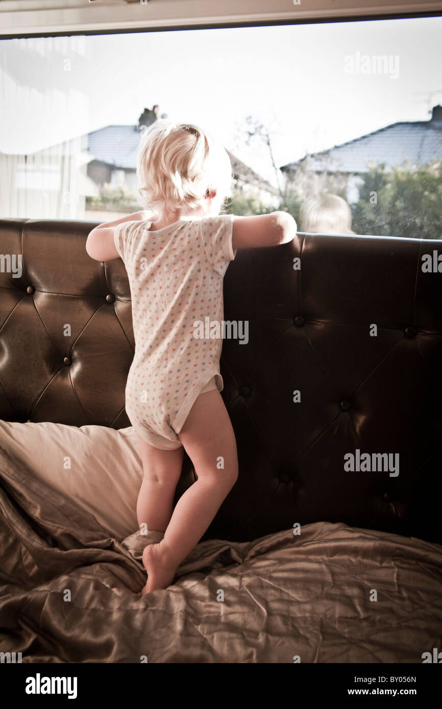 child stood on a bed looking out of the window Stock Photo - Alamy