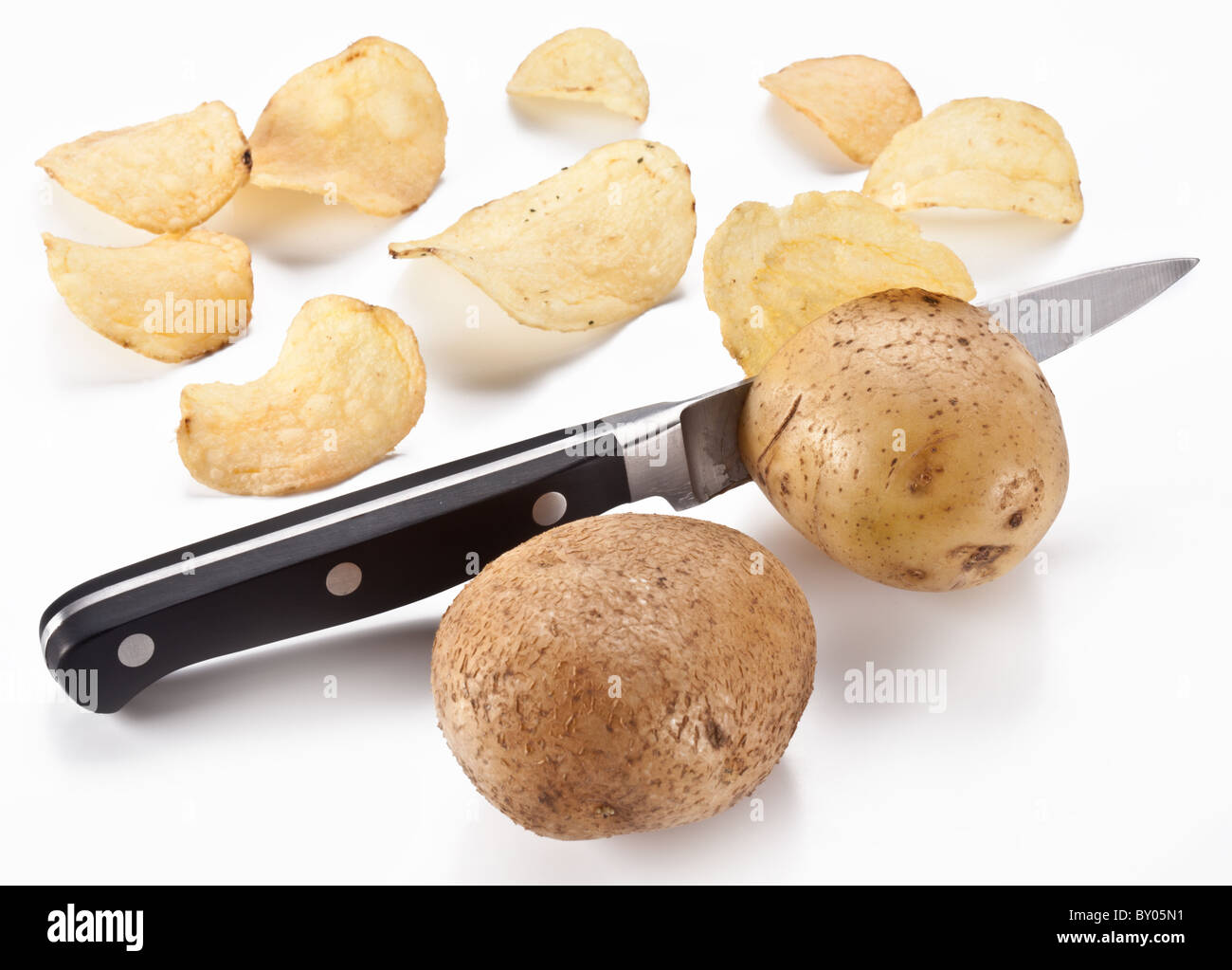 Conceptual image - the knife cuts fresh potatoes and potato chips are ...