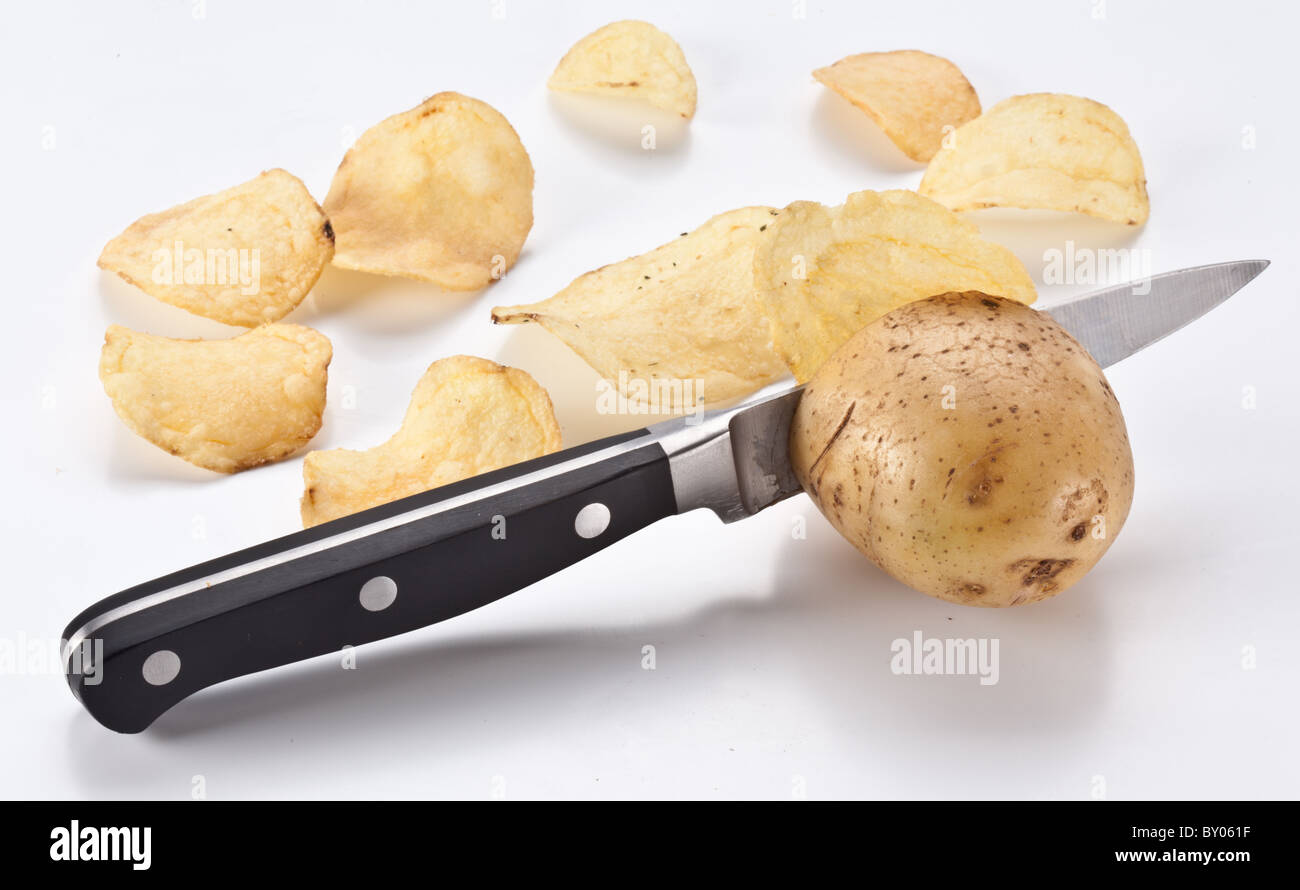 Conceptual image - the knife cuts fresh potatoes and potato chips are ...