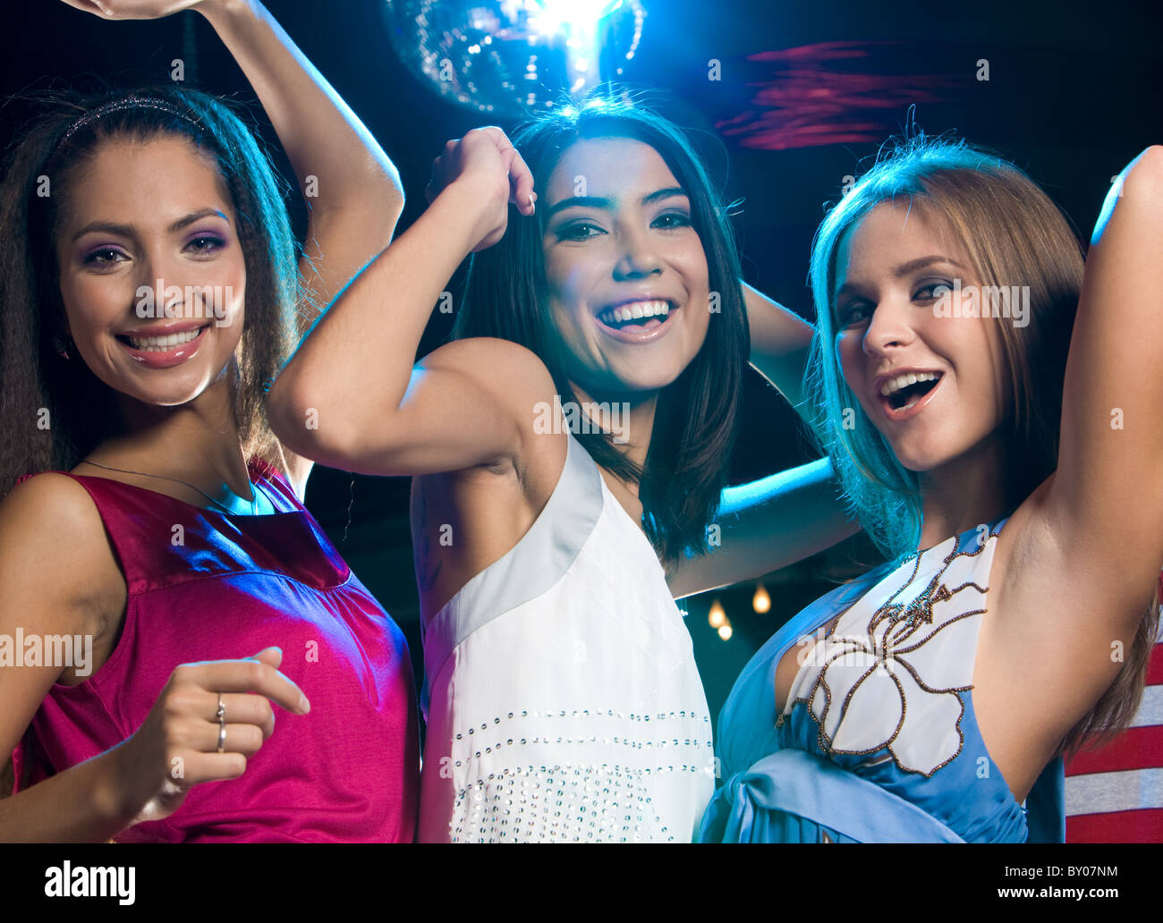 Portrait of three laughing girls dancing at disco in the night club ...
