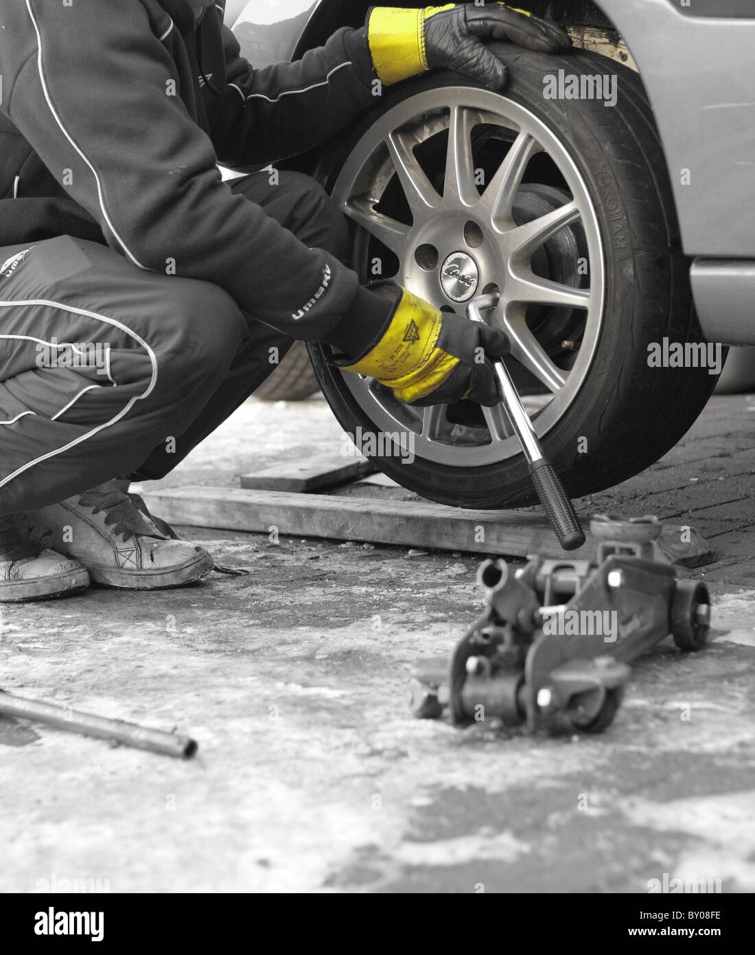 A mechanic unscrewing the wheel nuts with a wrench to remove the wheel ...