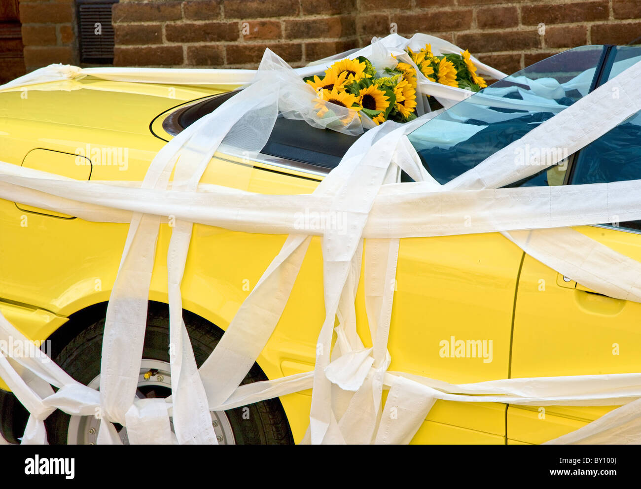 Paper ribbons festoon a yellow Alpha Romeo convertible car with ...