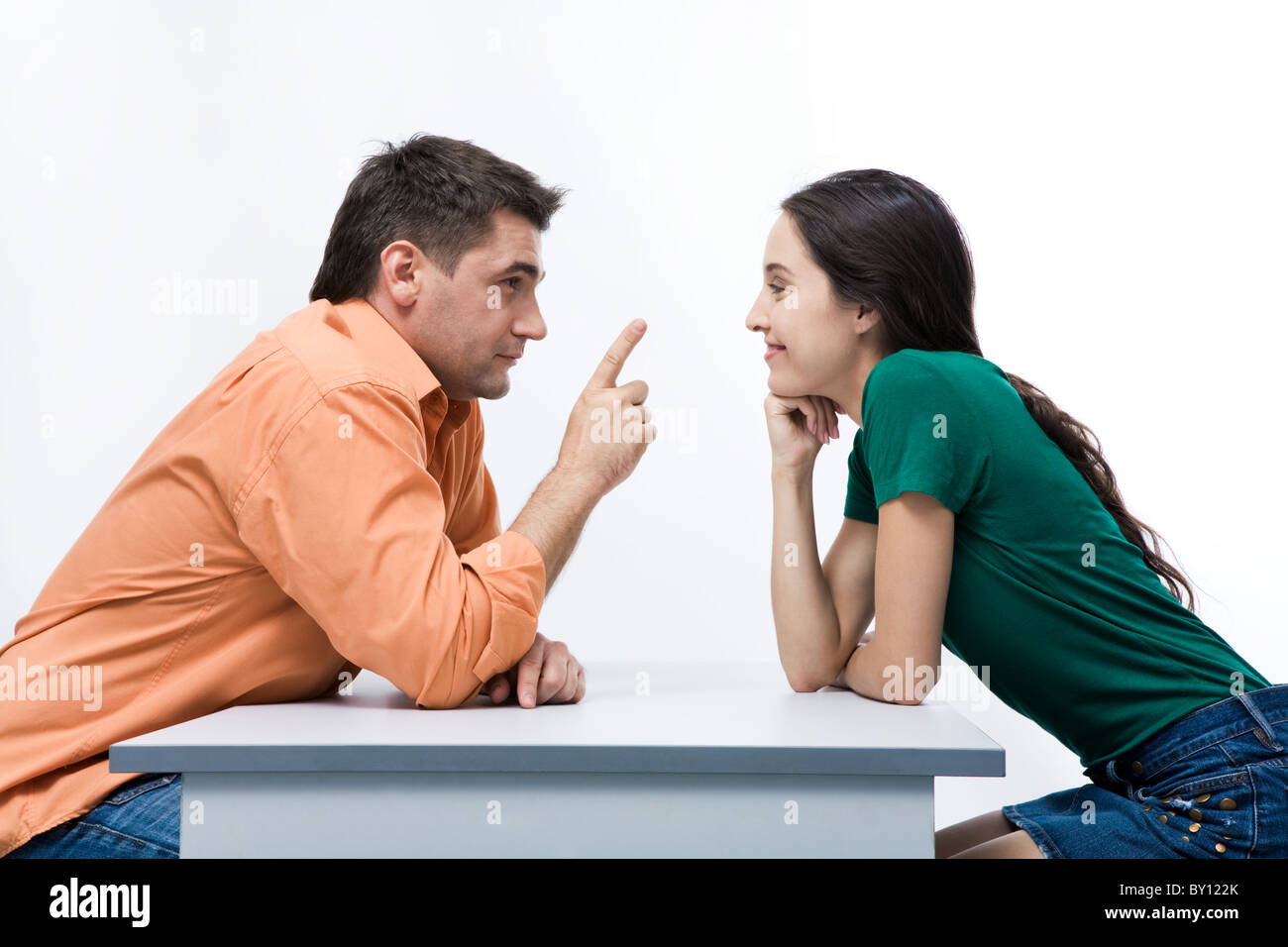 Smart man pointing upwards while explaining something to smiling girl ...