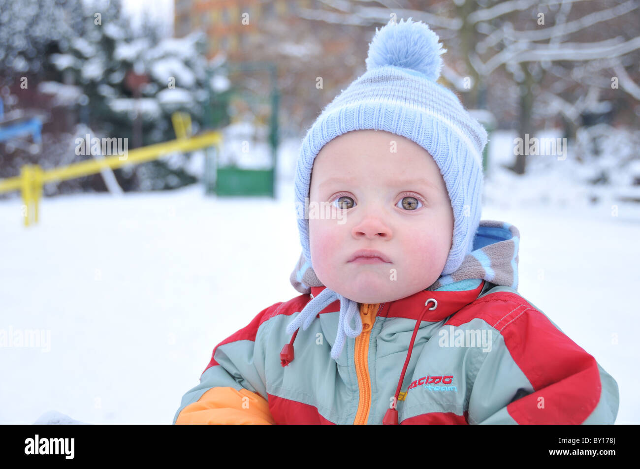 A little boy in winter clothes at a playground covered in snow Stock ...