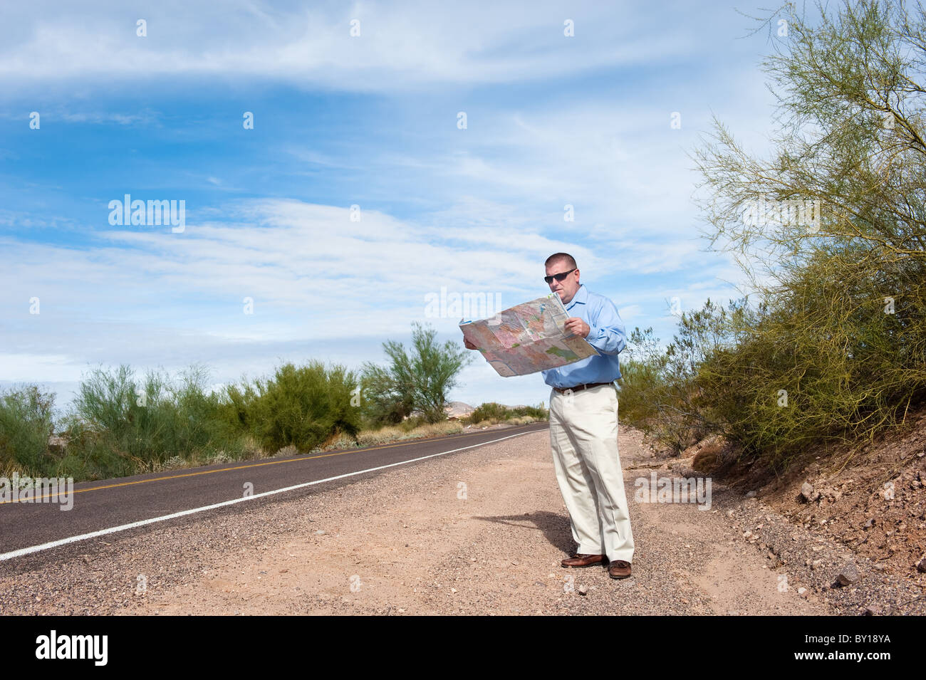A lost man stands alone on a deserted road reading a map Stock Photo ...
