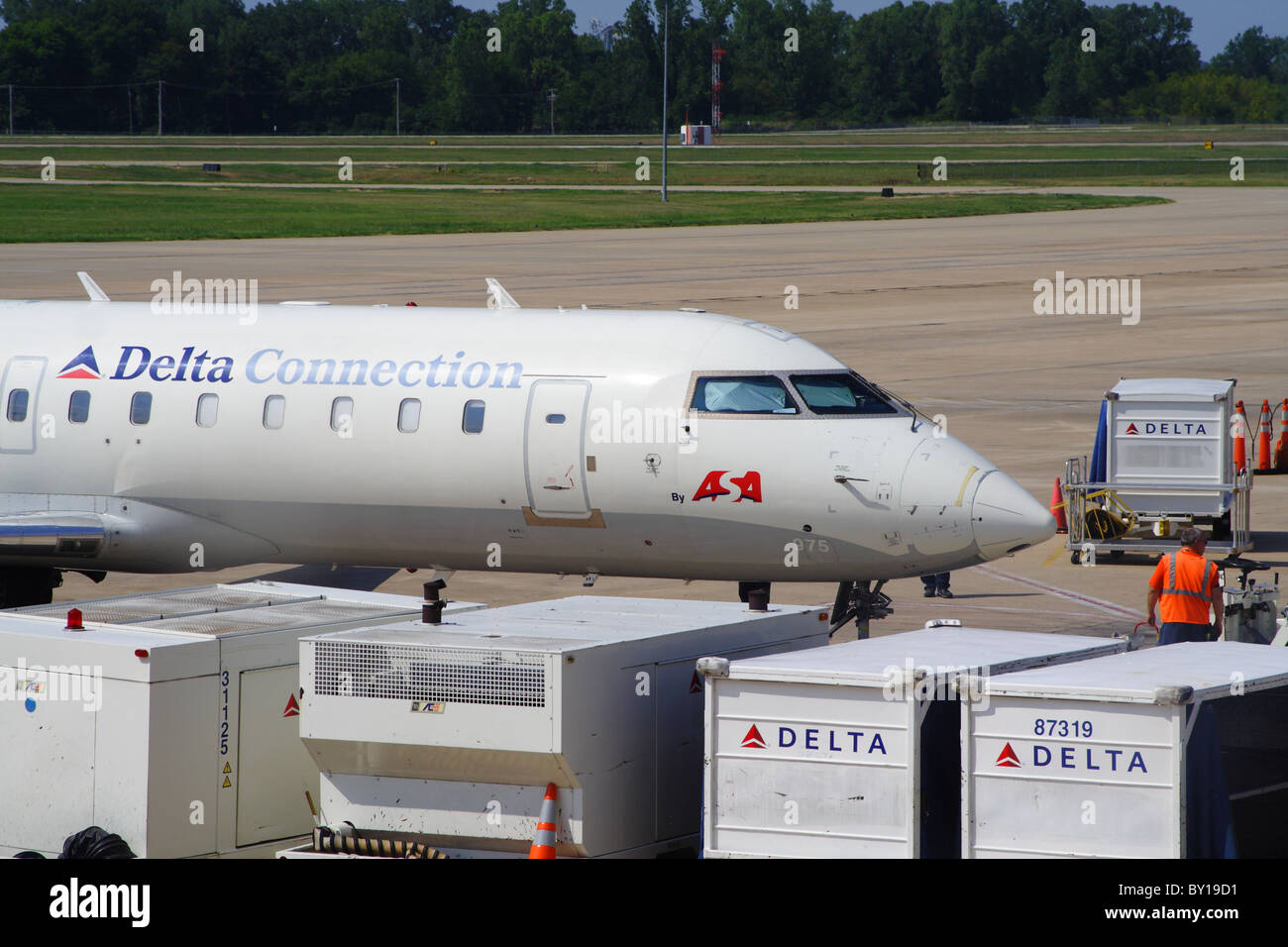 Delta Connection CRJ passenger jet and flightline worker wait at the ...