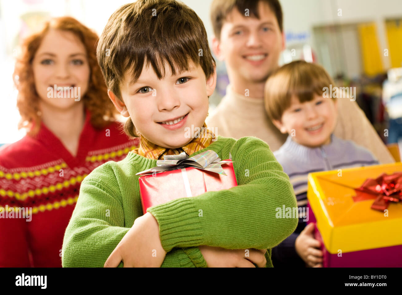 Portrait of glad boy with present looking at camera on background of ...