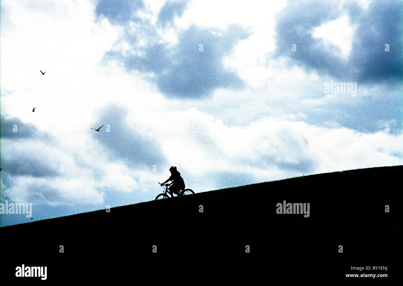 A silhouette of a person cycles down a hill Stock Photo - Alamy