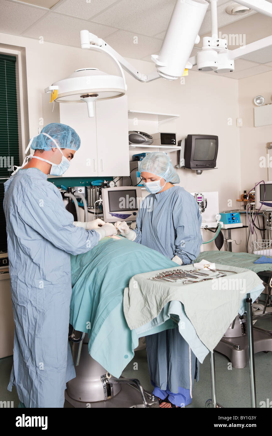 Two surgeons performing operation, surgical instruments in foreground ...