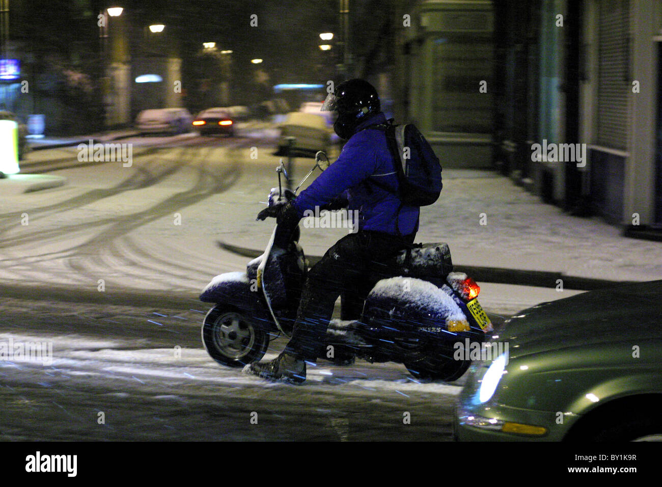 street scene with man on moped riding through snow Stock Photo - Alamy