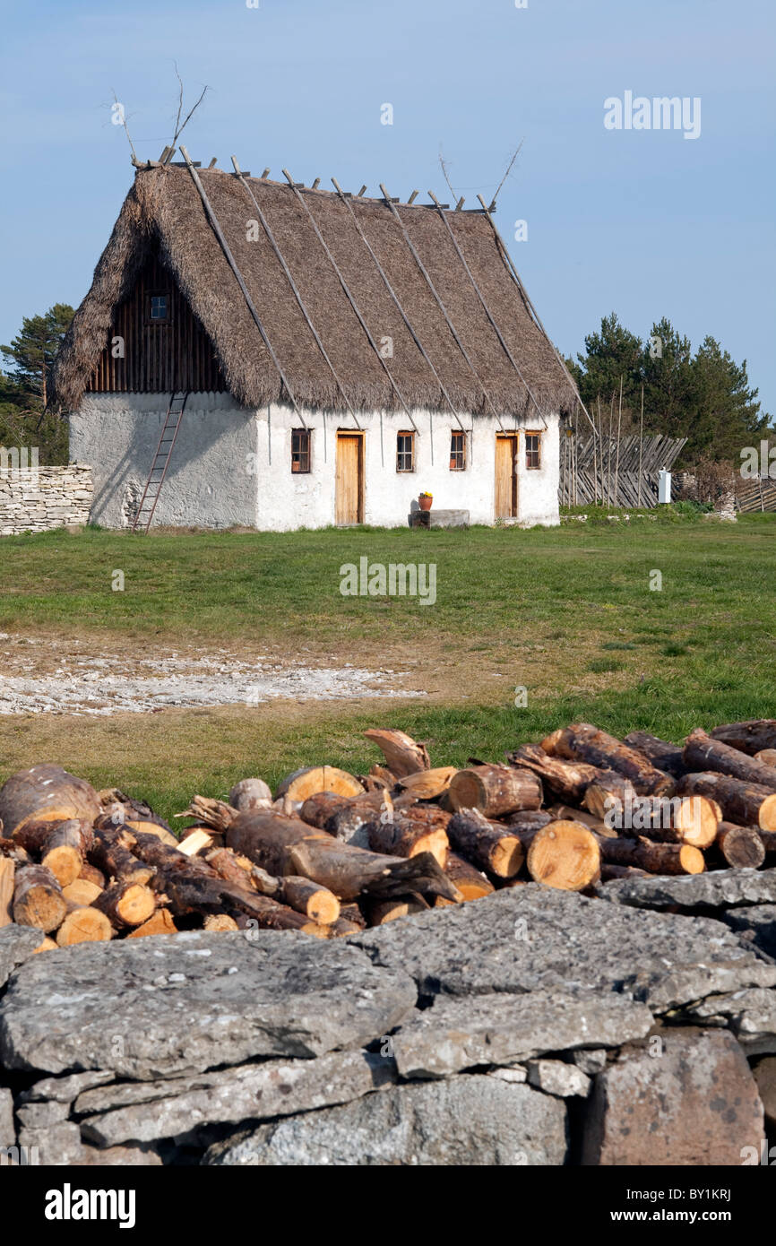 Sweden, Island of Gotland. Traditional farmhouse with winter wood pile ...
