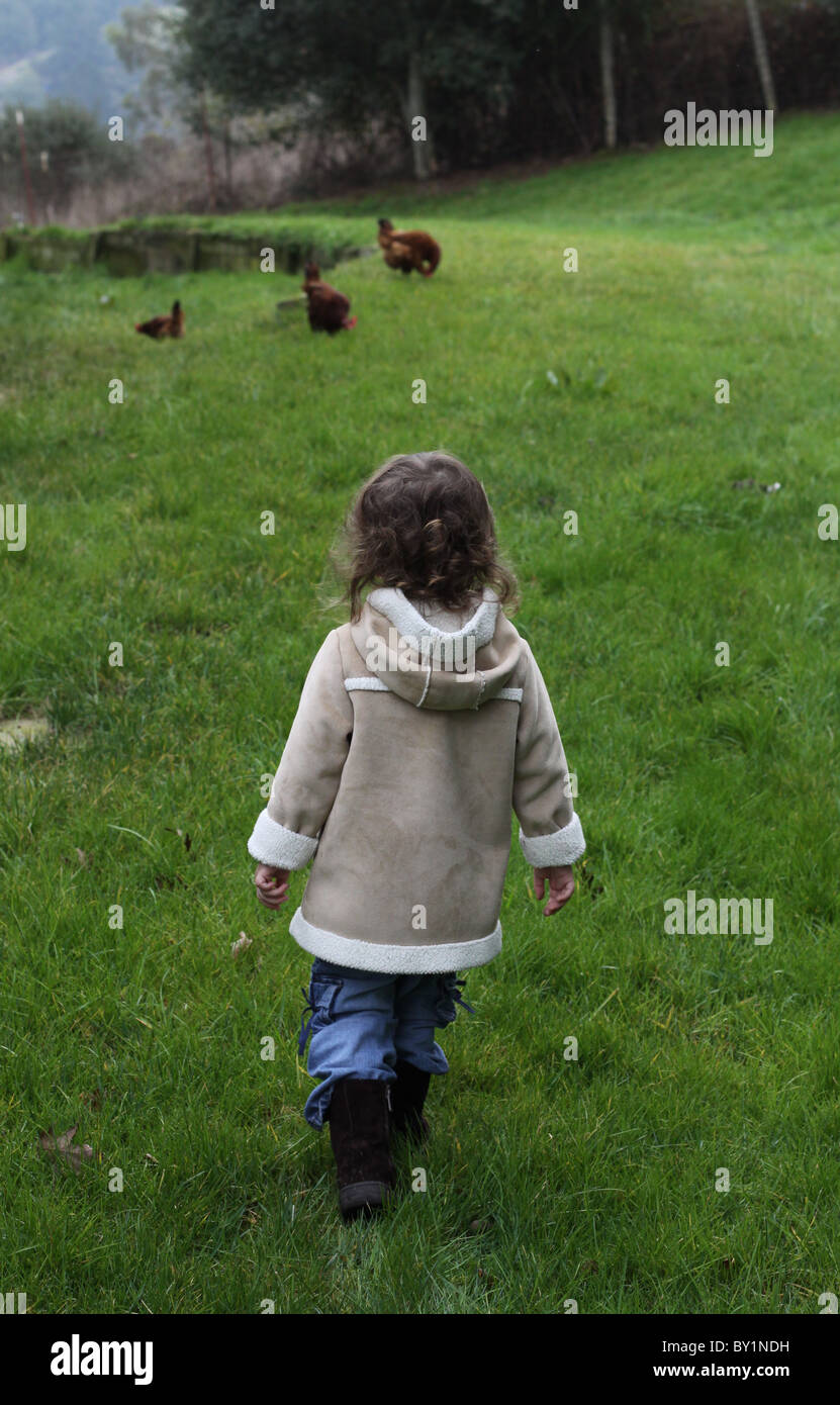 A small girl walking on a farm with chickens Stock Photo - Alamy