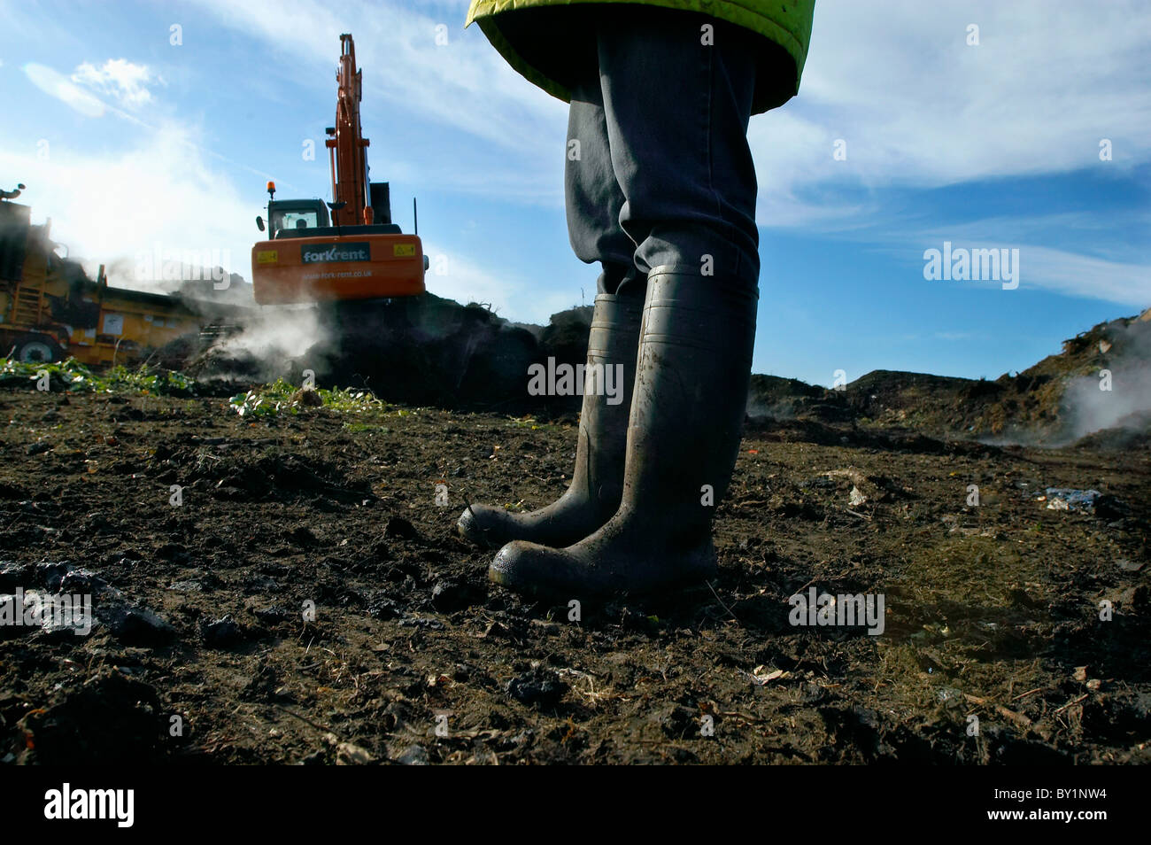 Legs of site warden with tracked excavator on landfill Stock Photo - Alamy