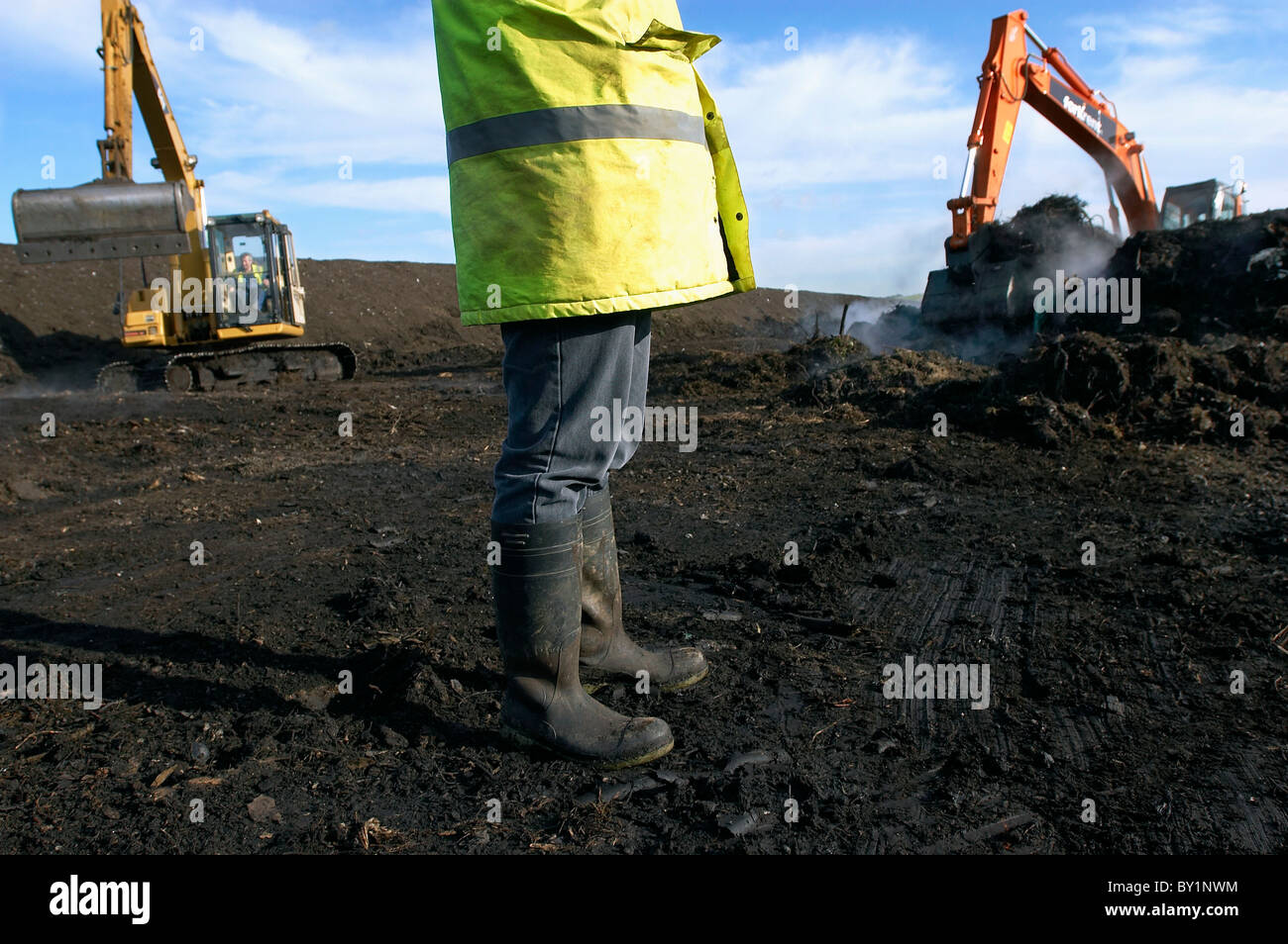 Legs of site warden with tracked excavator on landfill Stock Photo - Alamy