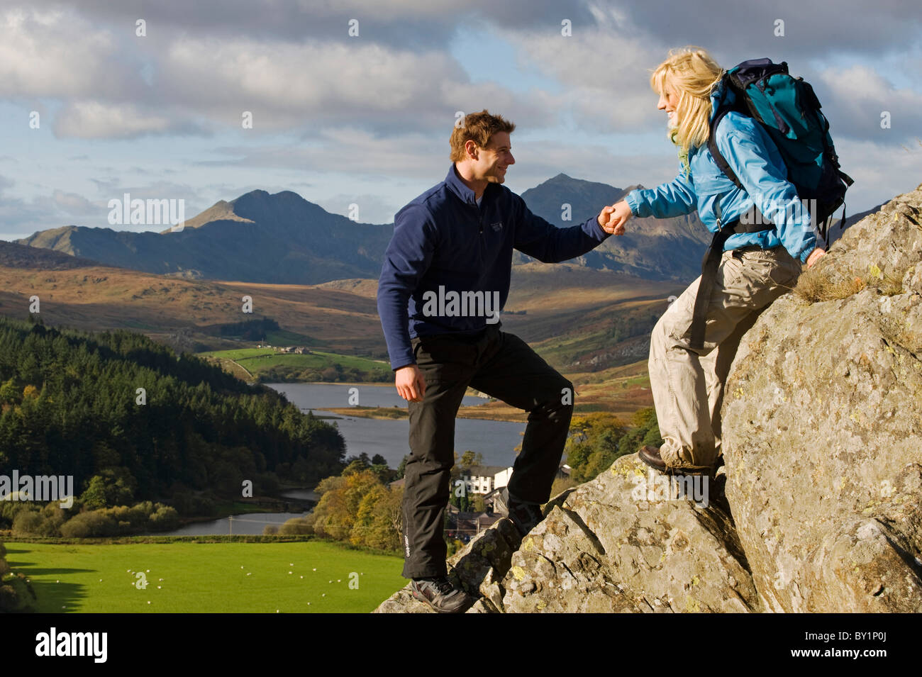 North Wales, Snowdonia. Man and woman scrambling on rocks against the ...
