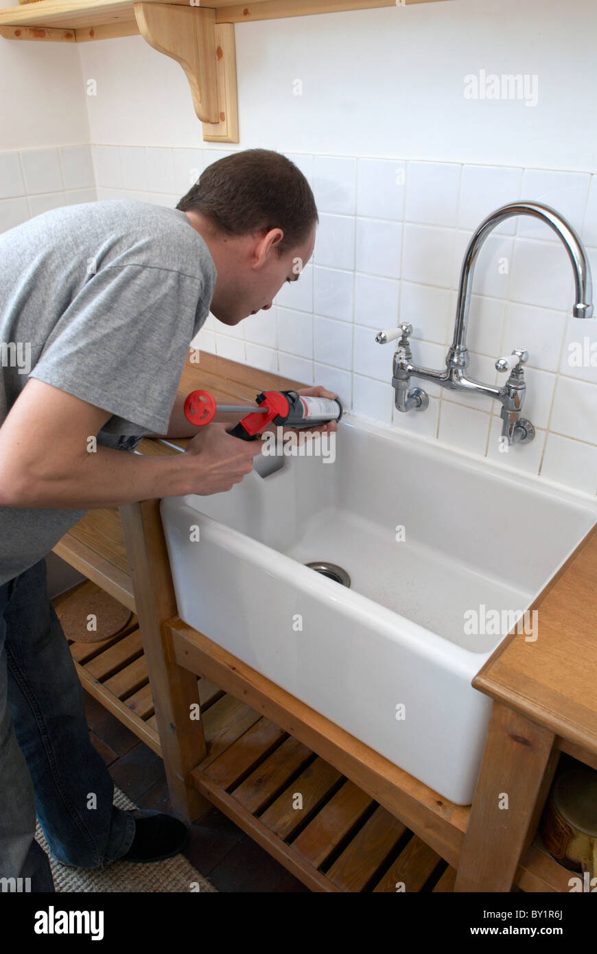 Man using sealant gun in a kitchen Stock Photo - Alamy