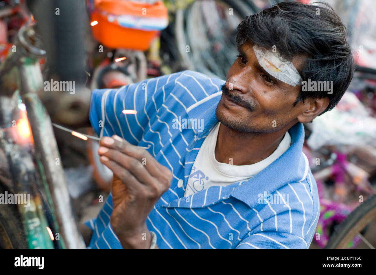 A man fixing a bicycle at a market in Bhopal, India Stock Photo - Alamy