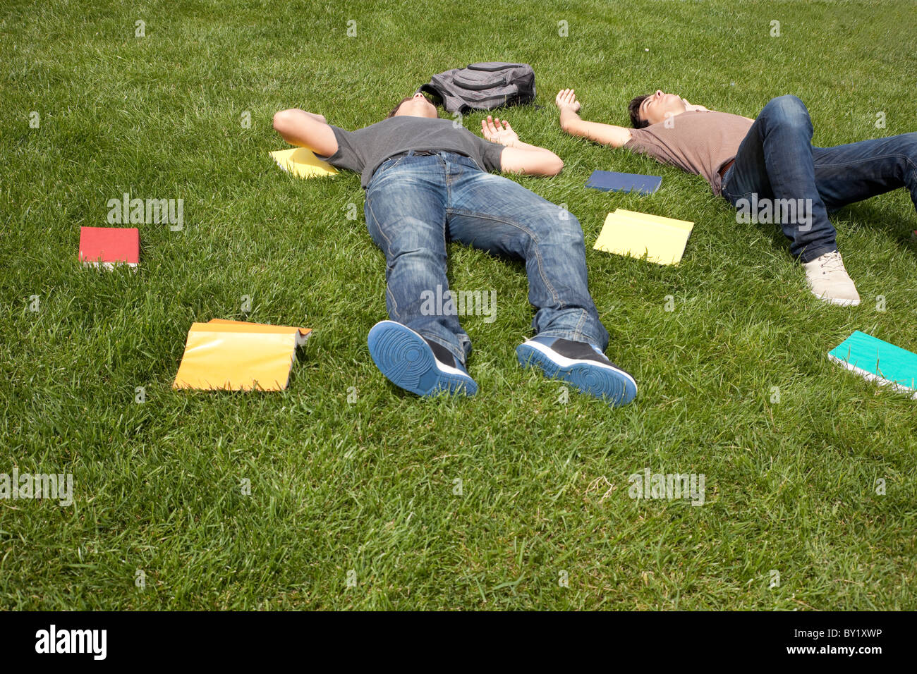 two young student lying down at the school grass after long hours of ...