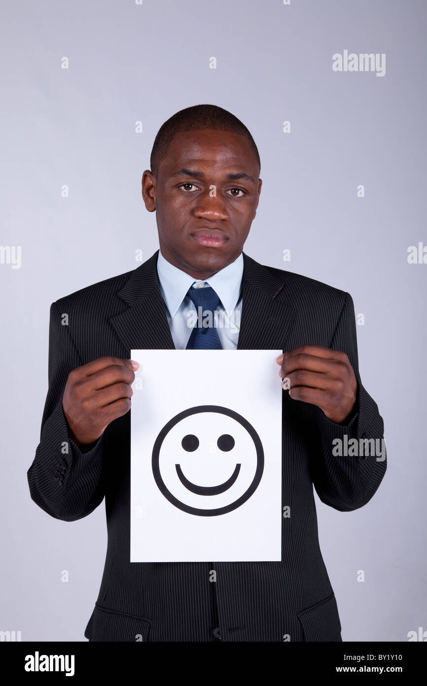 serious african businessman holding a smile symbol printed on a paper ...