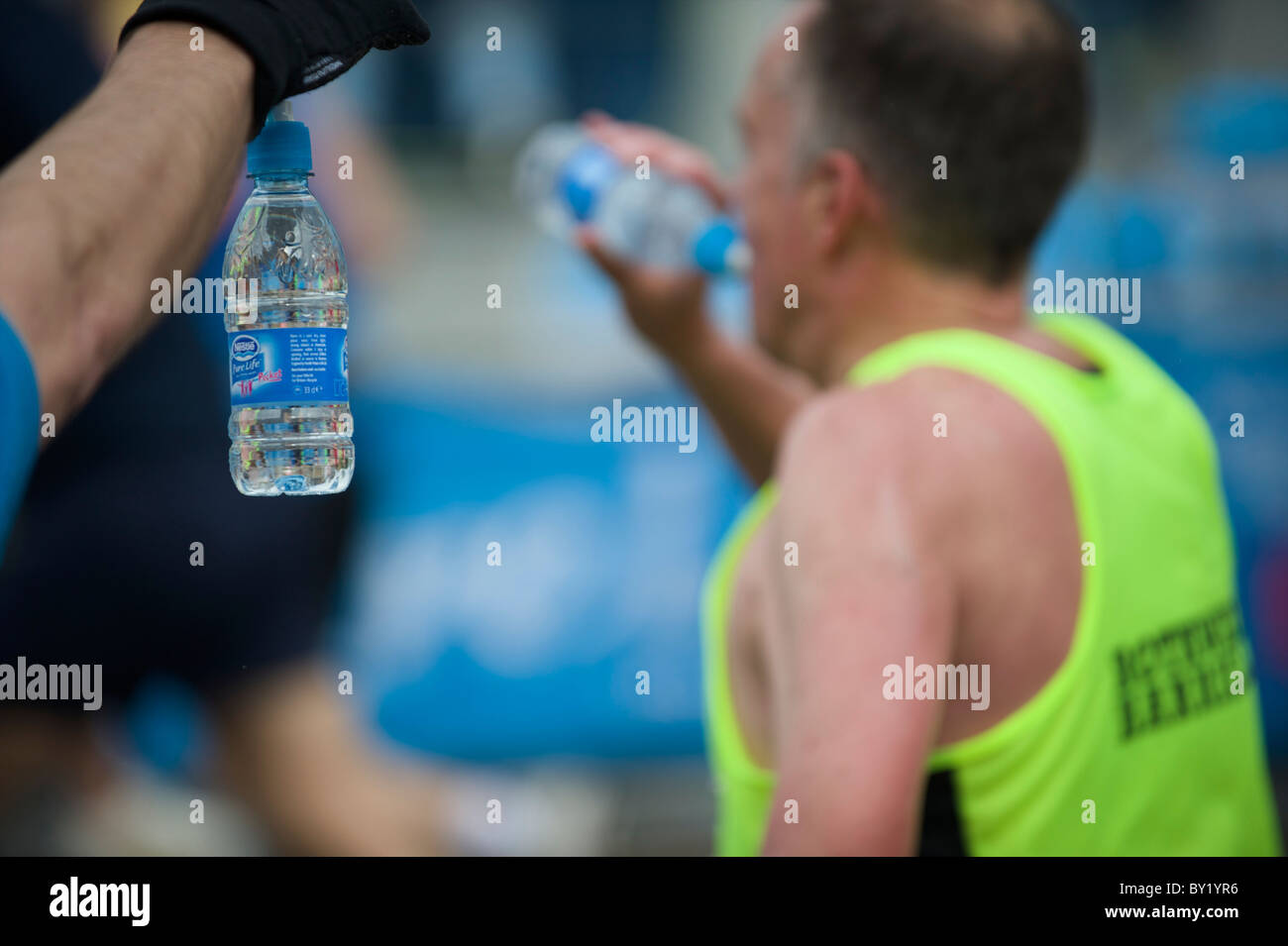 Volunteers offer bottled water to runners at the mile 6 marker of the ...