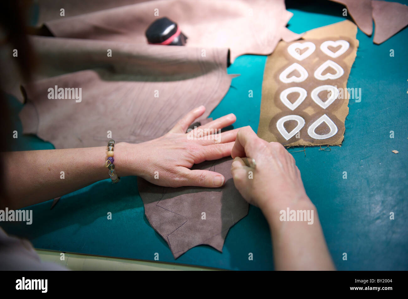 A shoemaker works on a pair of shoes in fashion designer Jimmy Choo's ...