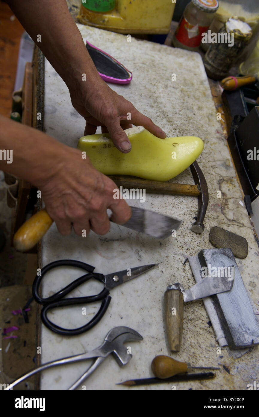 A shoemaker works on a pair of shoes in fashion designer Jimmy Choo's ...