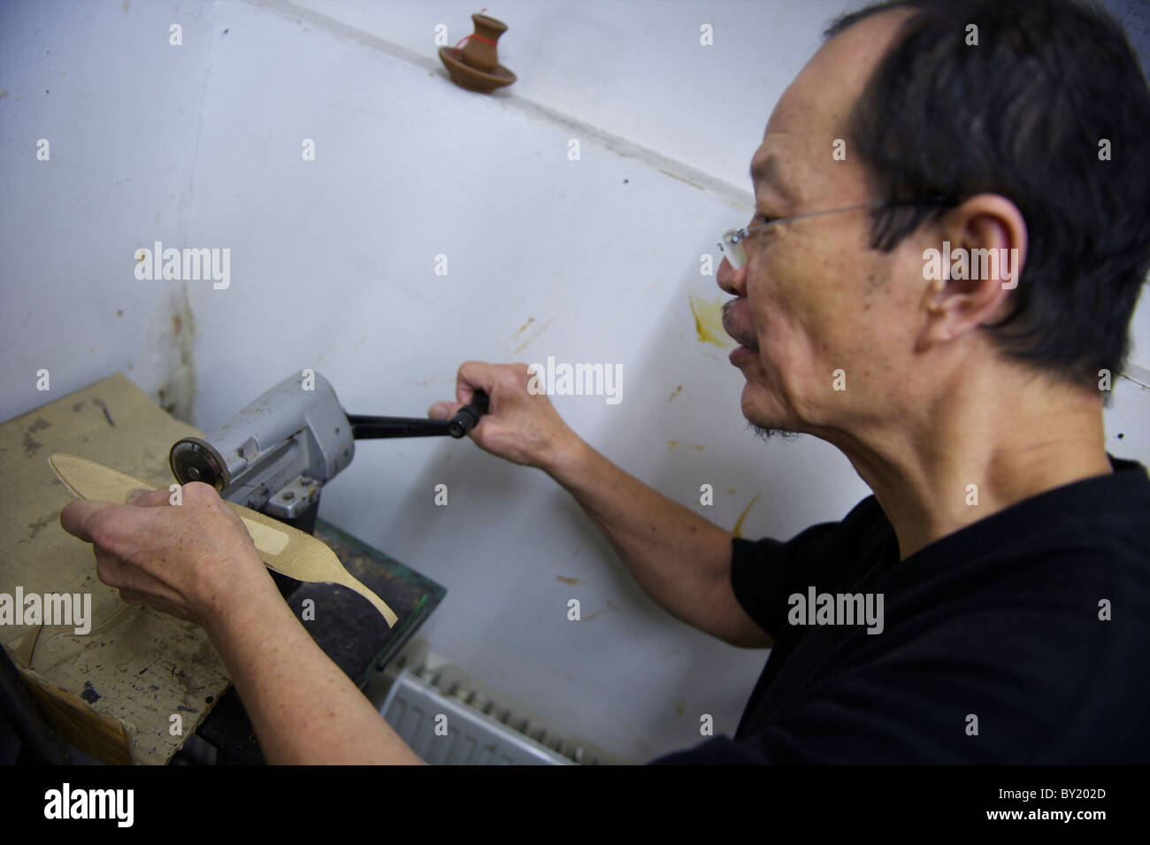 A shoemaker works on a pair of shoes in fashion designer Jimmy Choo's ...