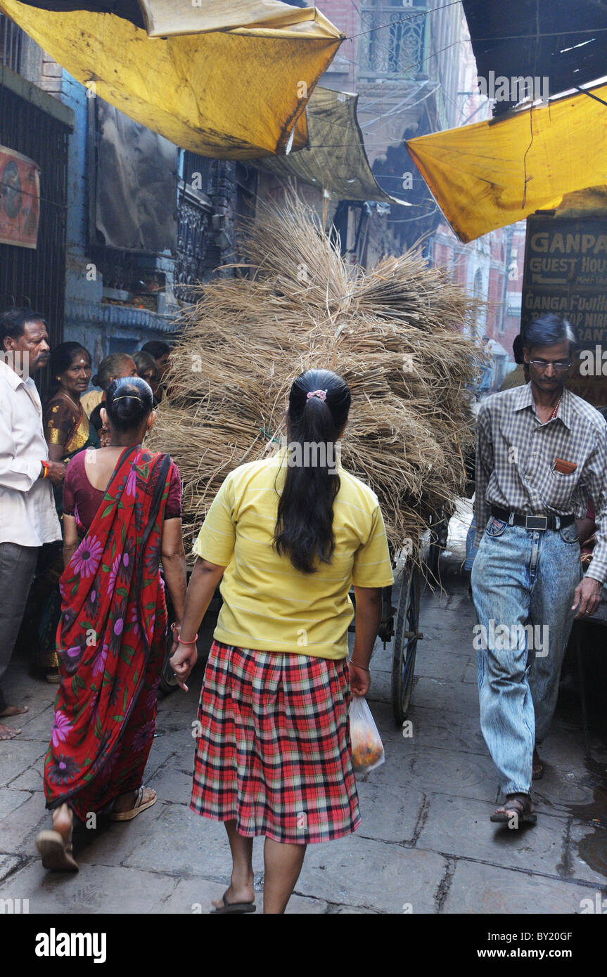 Two women pushing a full cart through narrow streets in Varanasi, India ...