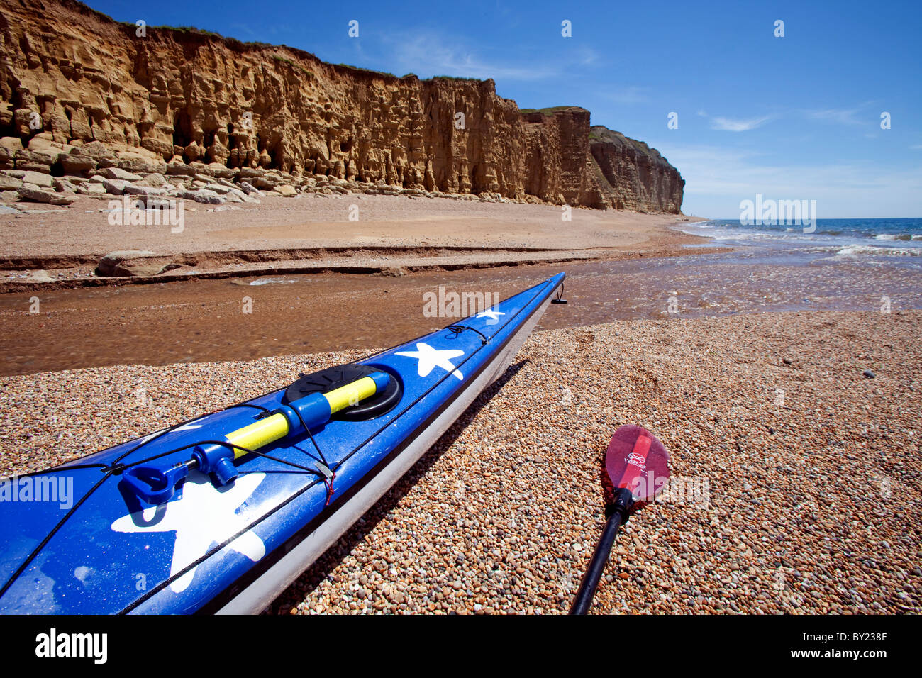 England, Dorset, Bridport. A sea kayak rests in the shadow of the ...