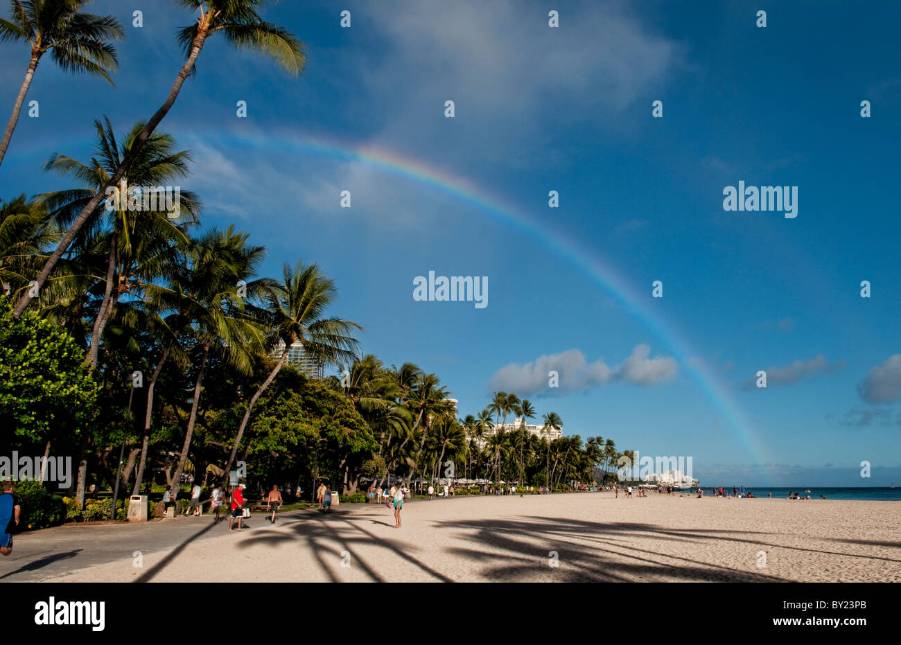 Rainbow and palm shadow on Waikiki Beach near the Hilton Hawaiian Village in Honolulu Hawaii in ...
