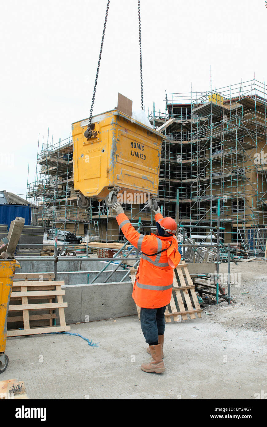 Worker guiding skip with recycling material Stock Photo - Alamy