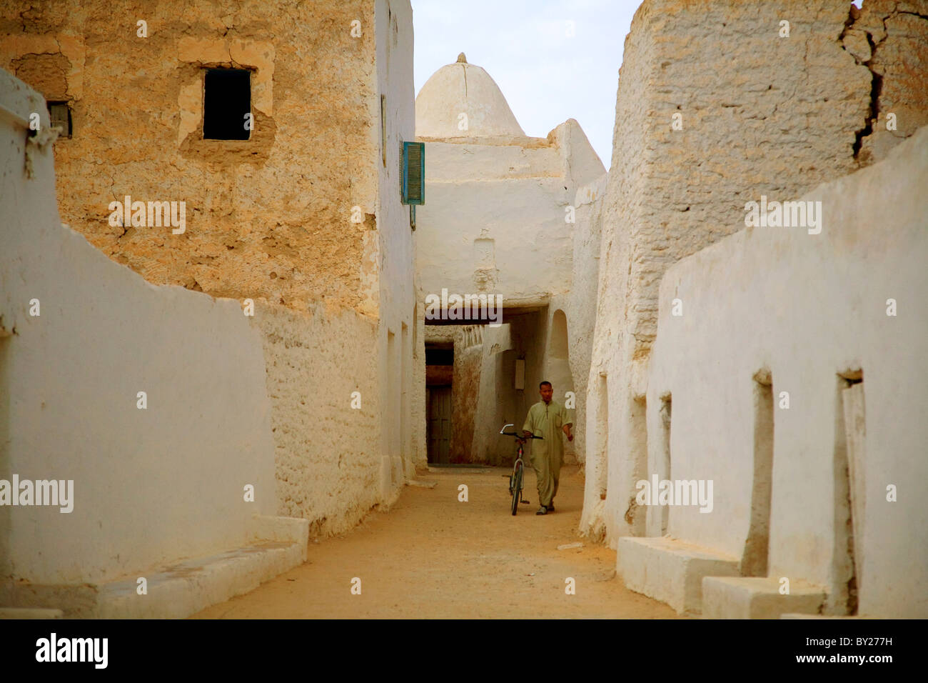 Ghadames, Libya; A man walking with his bicycle through unique the mud ...