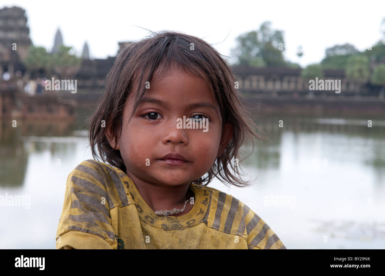 Young Poor Girl Aged 4 In Front Of River At Famous Angkor Wat In Siem Reap Cambodia In Asia
