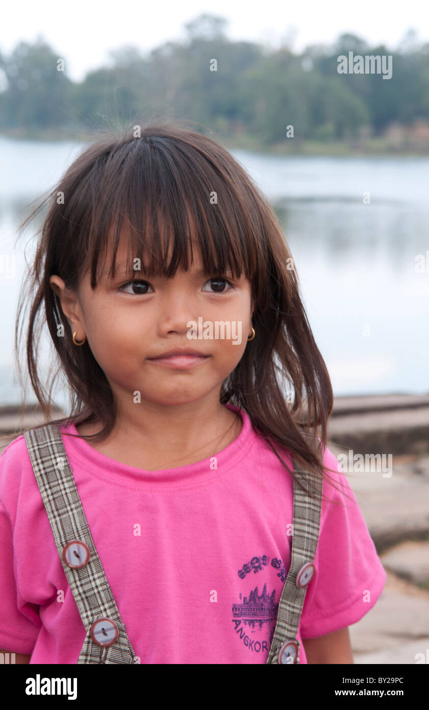 Young poor girl aged 5 in front of river at famous Angkor Wat in Siem ...