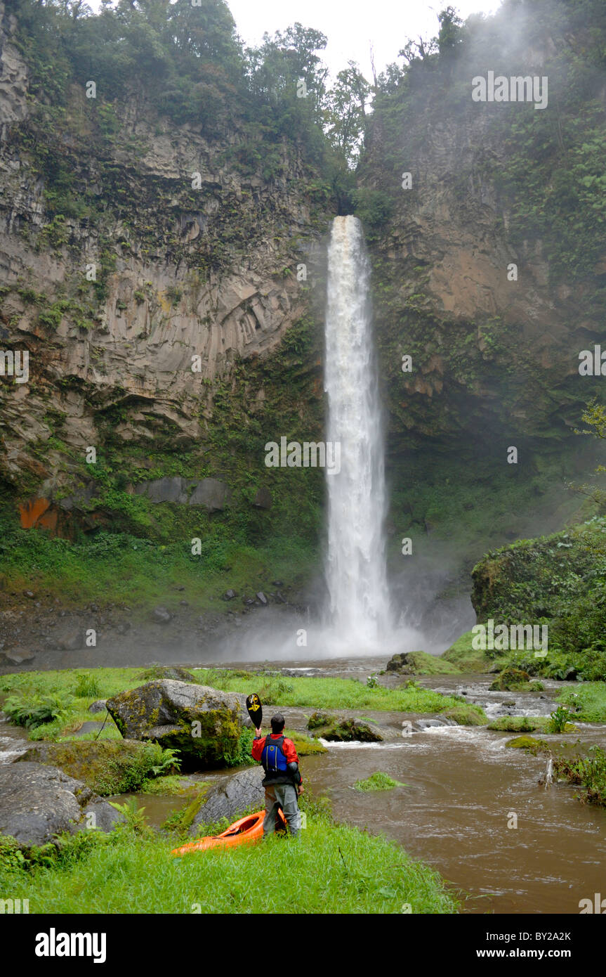 A kayaker hikes through the jungle carrying his kayak looking for new ...